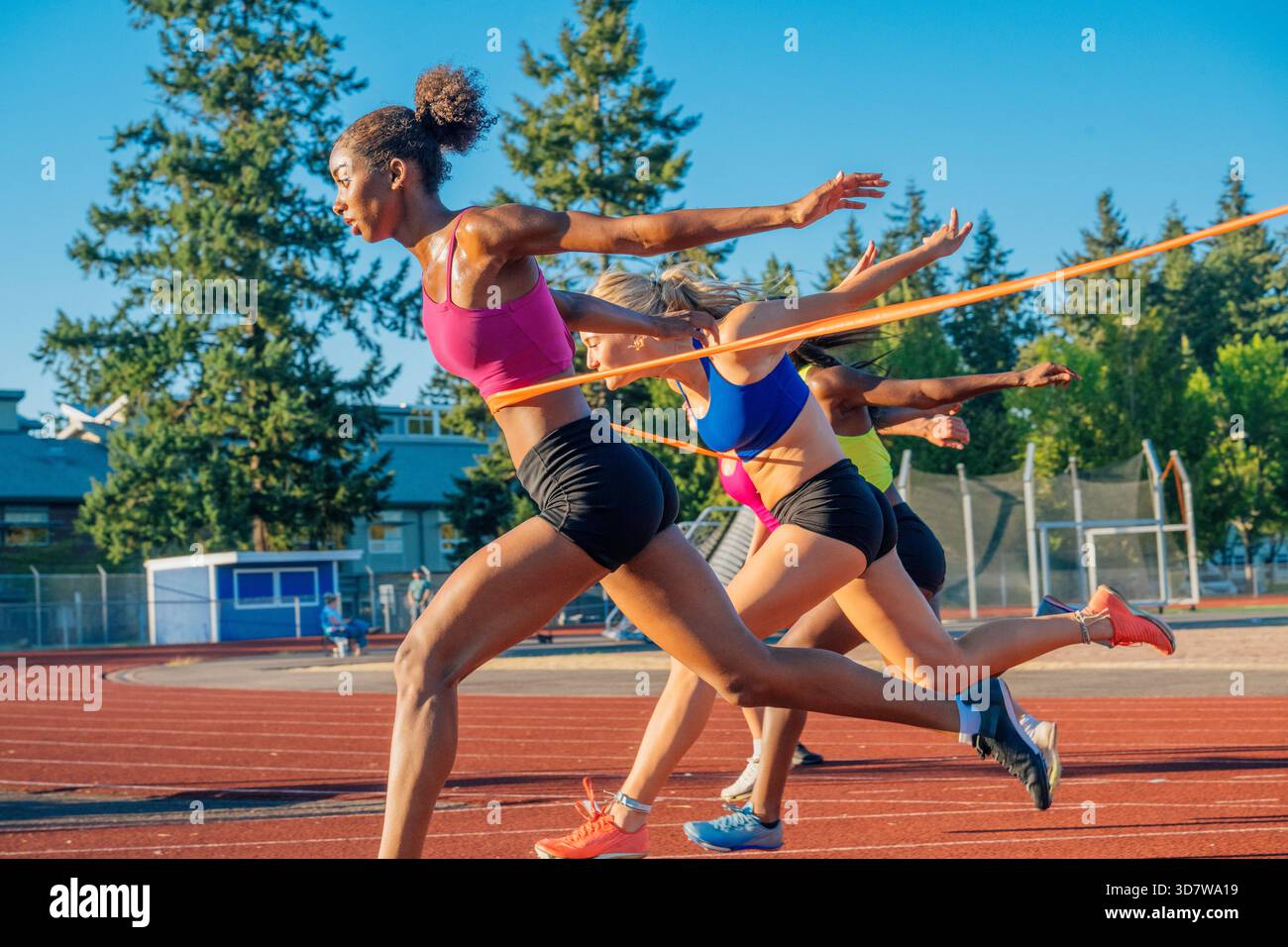 Female athletes sprinting across a finish line on a vibrant outdoor ...
