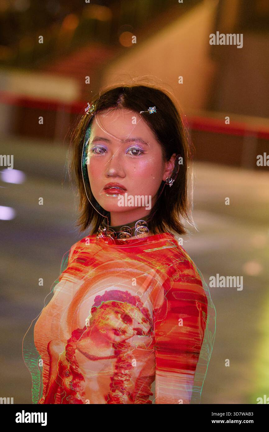 Woman in vibrant attire with projected geometric pattern on face stands ...
