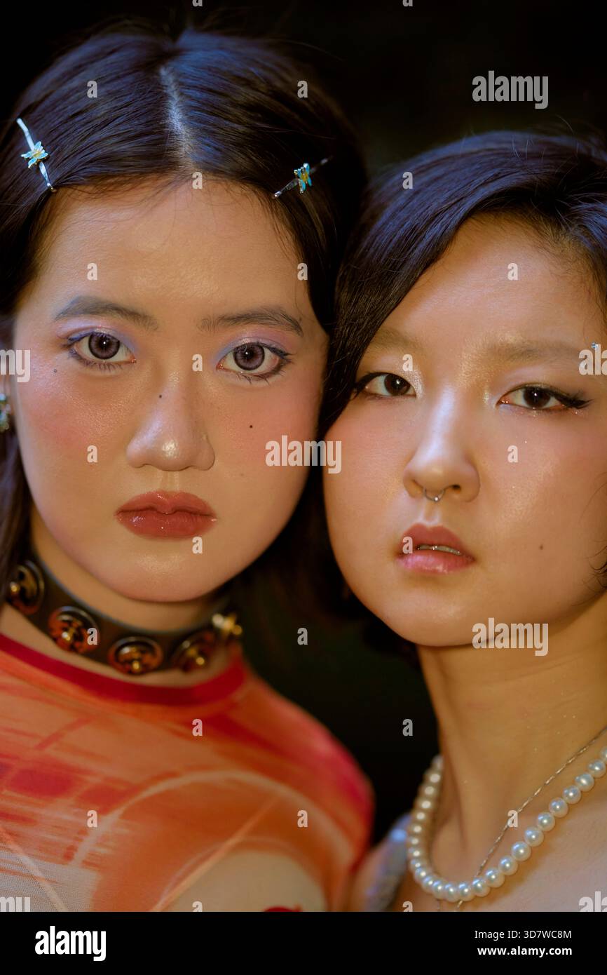 Two young women with bold makeup and hairstyles, close together, in a ...