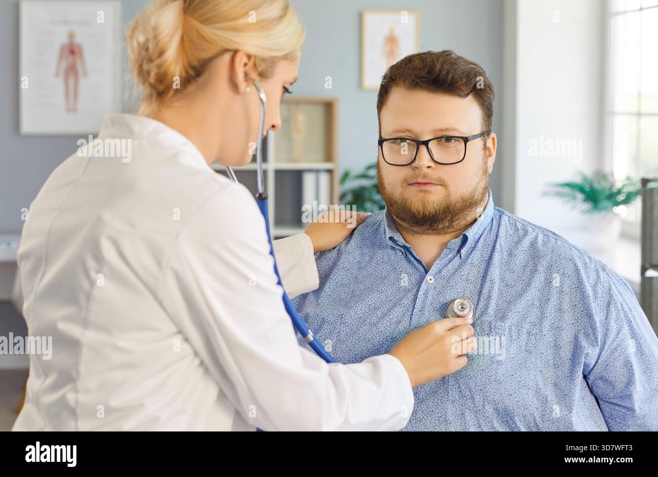 Doctor using stethoscope to examine male patient during routine clinic ...