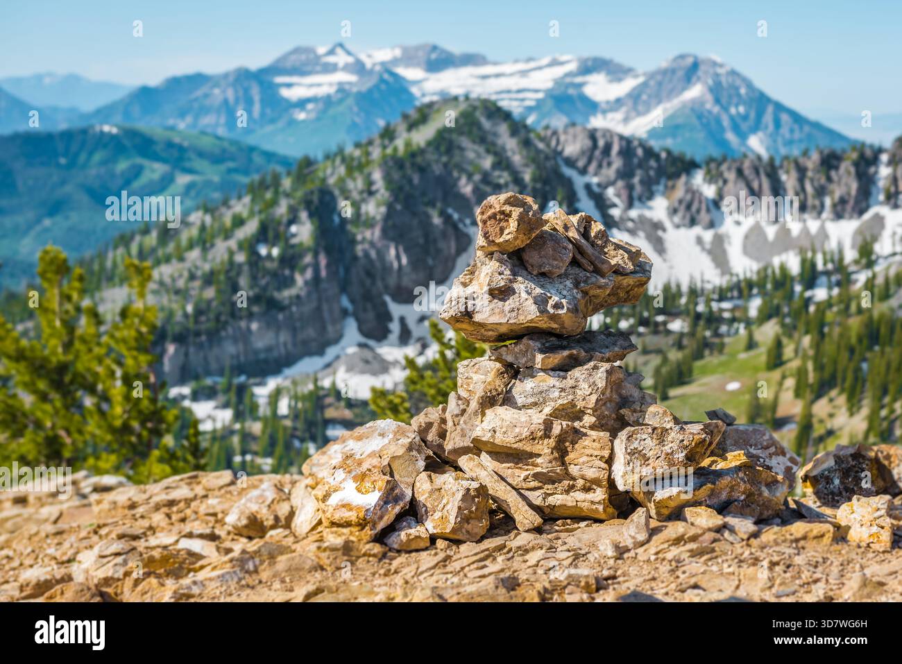 Stone cairn trail marker with snow-capped mountain peaks backdrop ...