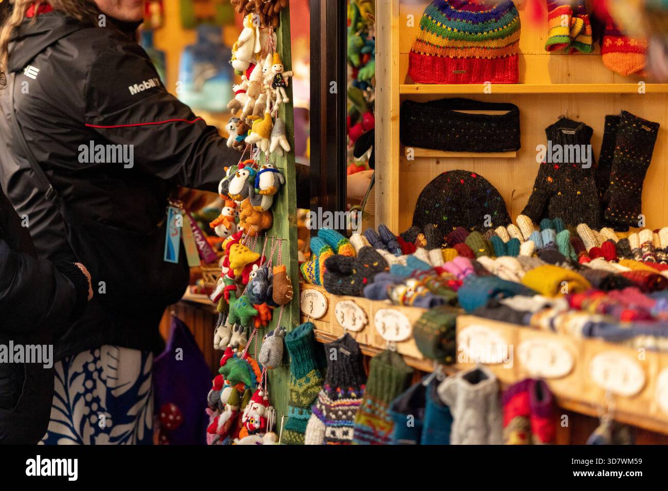 A stall with knitted goods. A visitor is looking at the merchandise ...