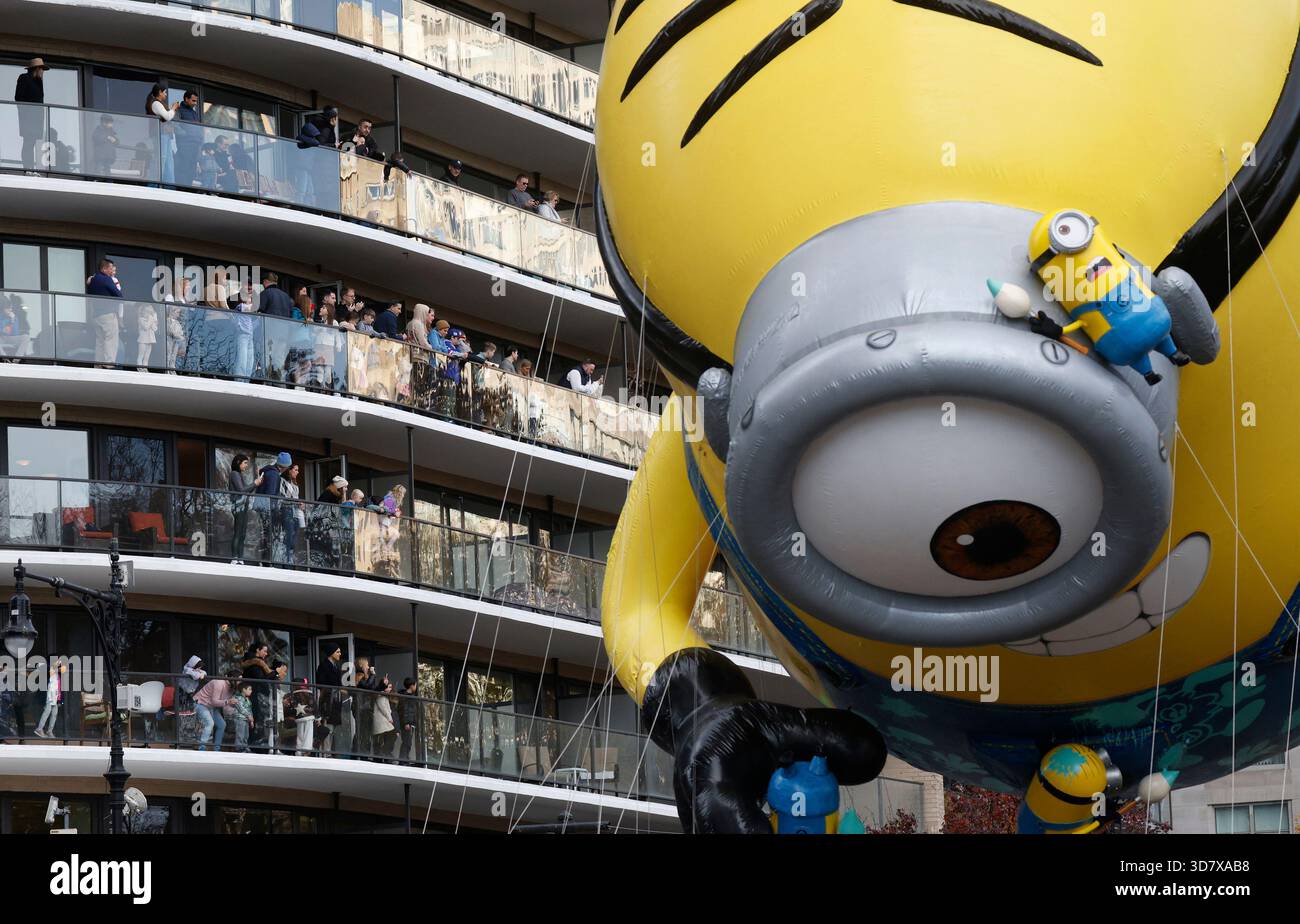 People watch from balconies as the Stuart the Minion balloon makes its ...