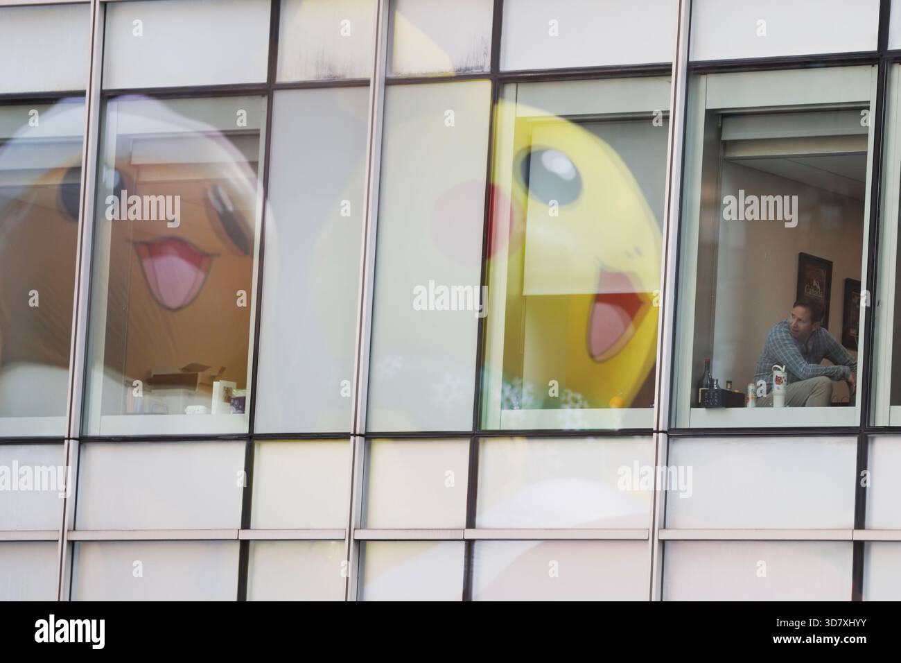 People inside office buildings watch as the Pikachu balloon passes ...