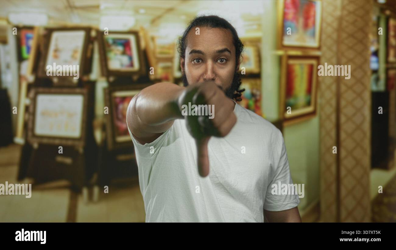 Man giving thumbs up with extended thumb and friendly smile in gallery ...