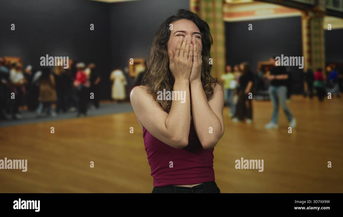 Woman covers mouth with hands while laughing inside large building ...