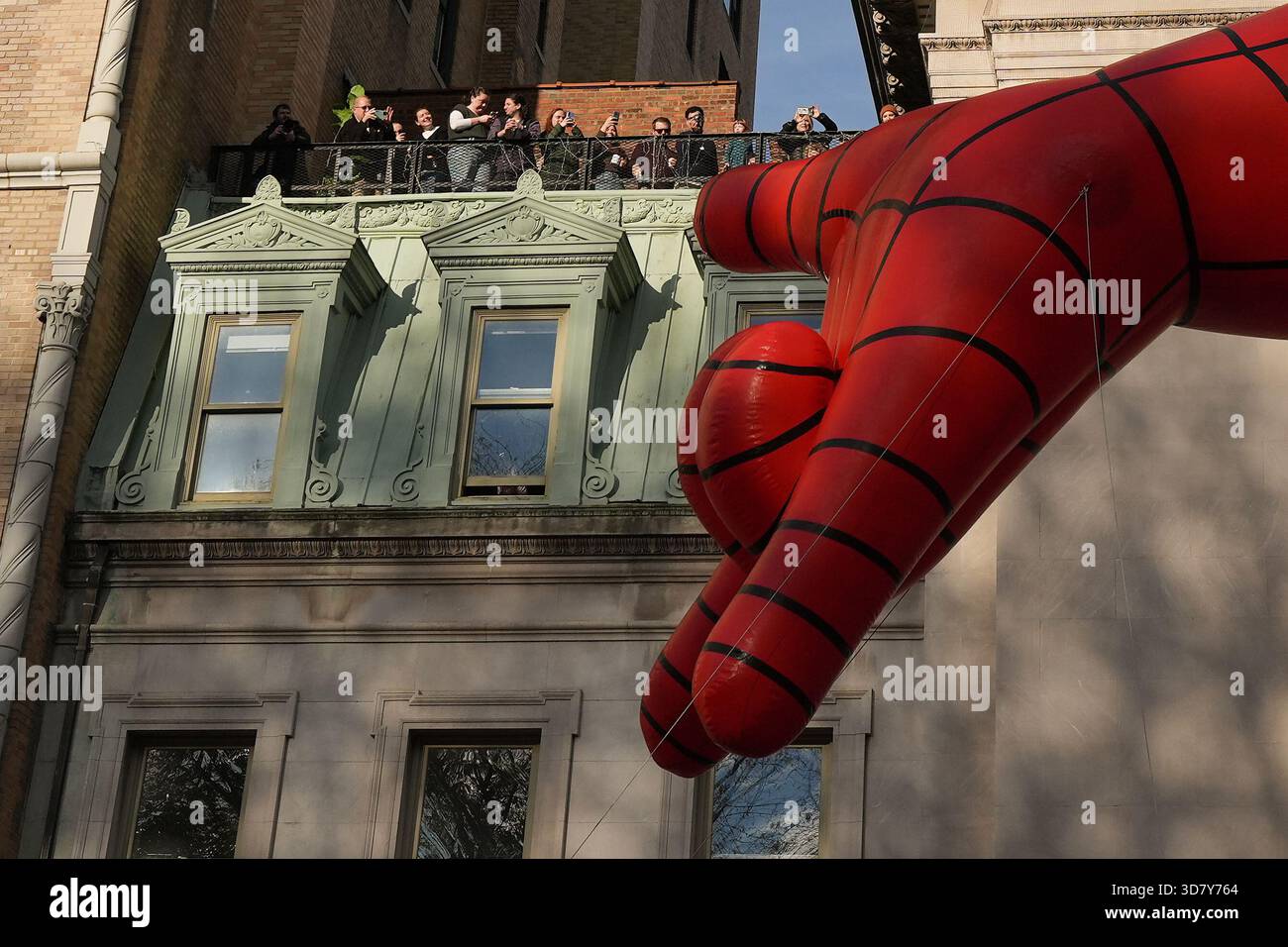 Spectators watch from a rooftop as the Spider Man balloon floats by on ...