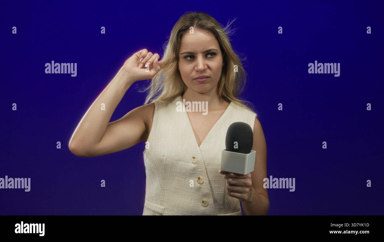 Woman reporter holding microphone with finger to temple, blonde hair ...