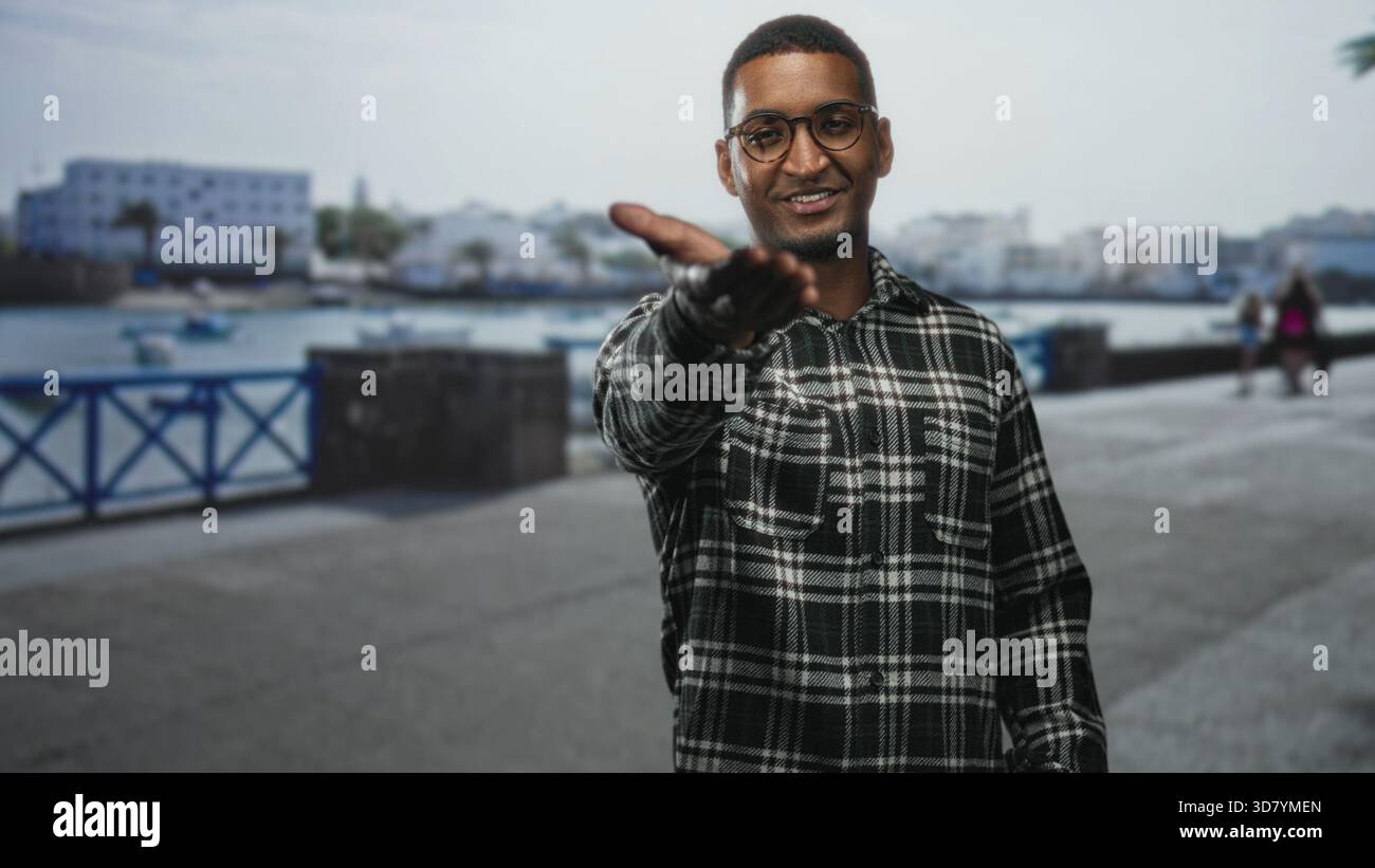 Man extends hand palm out on waterfront street wearing glasses and ...