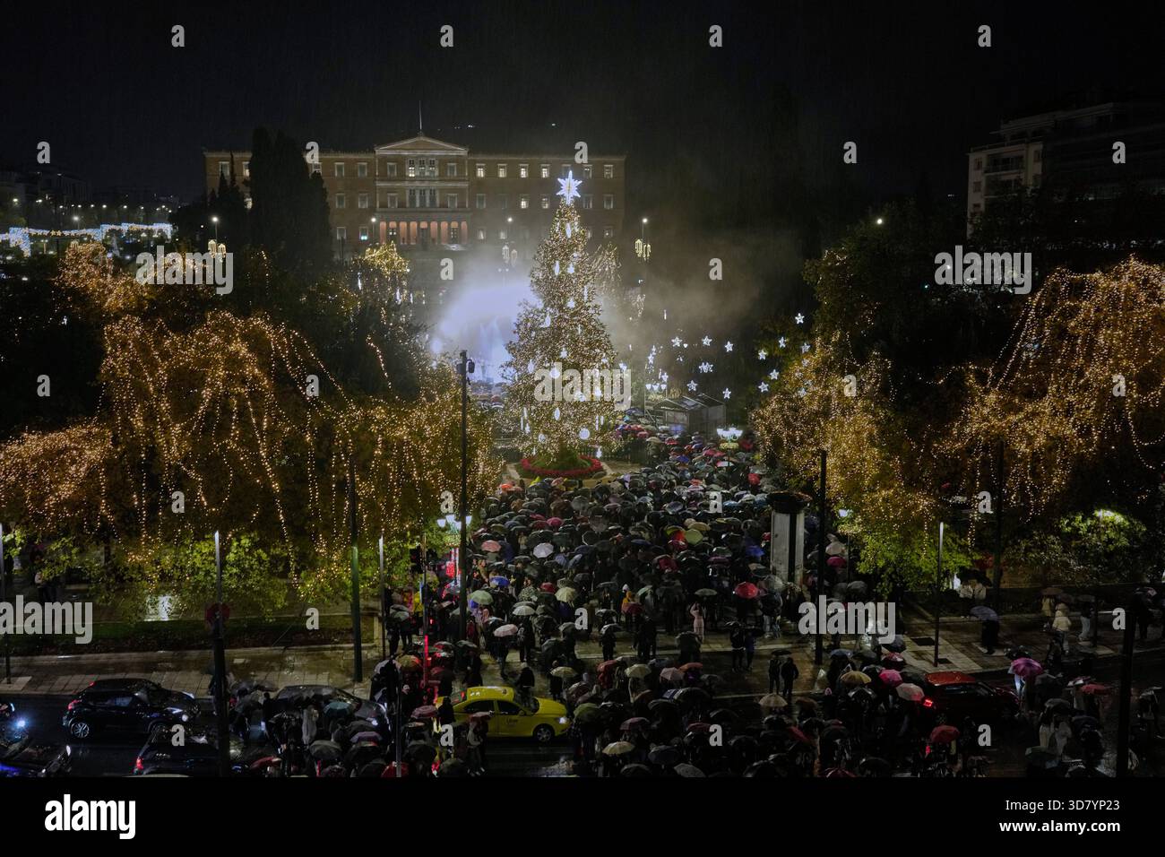 People gather under rainfall as the city of Athens illuminated its ...