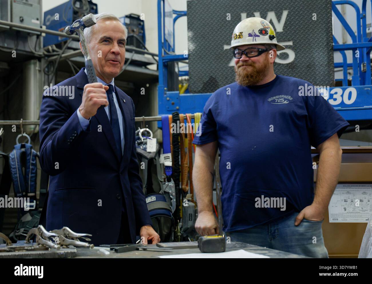 Prime Minister Mark Carney wields a hammer while meeting with ...