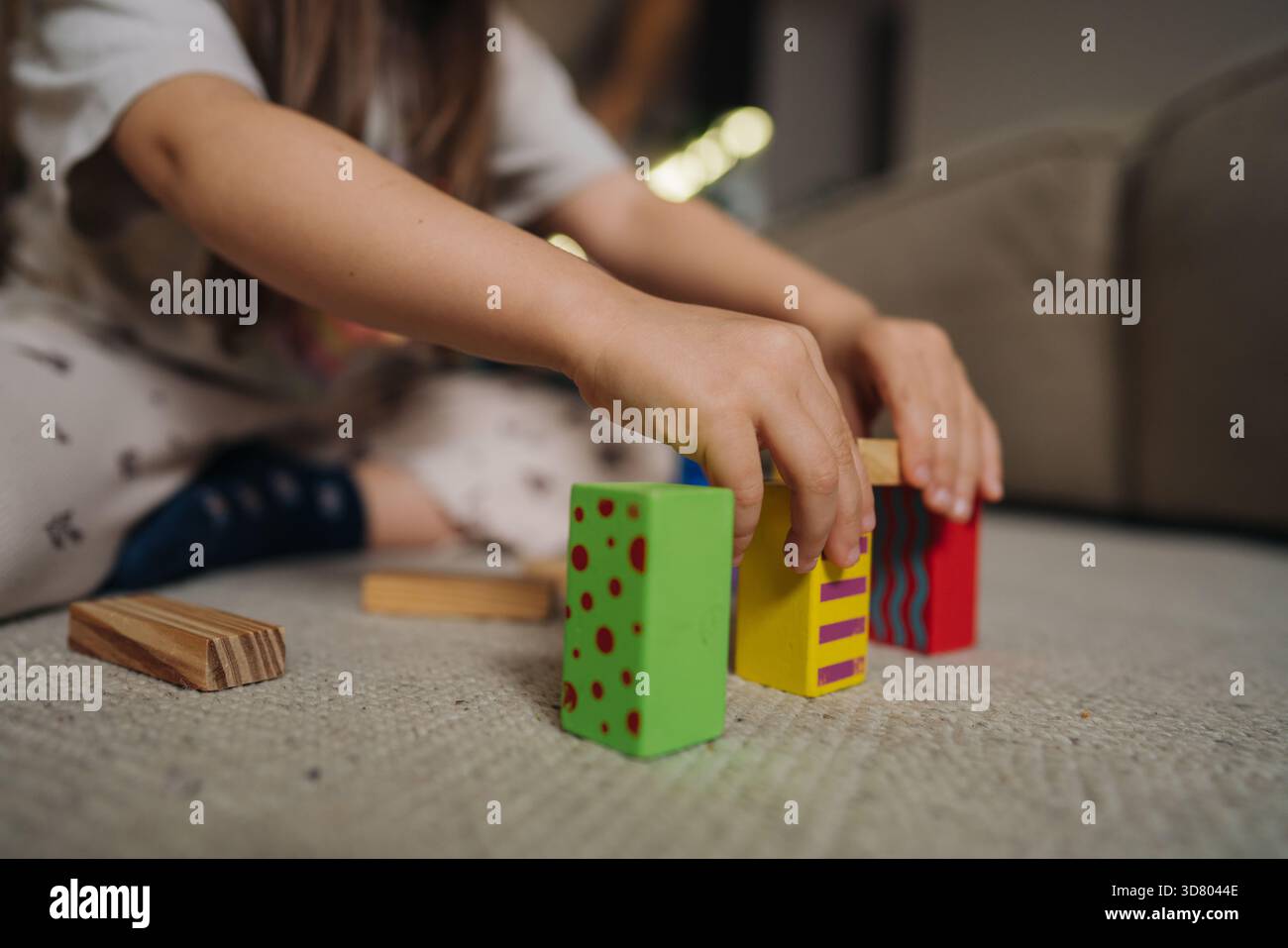 child stacking toys, calm indoor scene shows girl carefully arranging ...