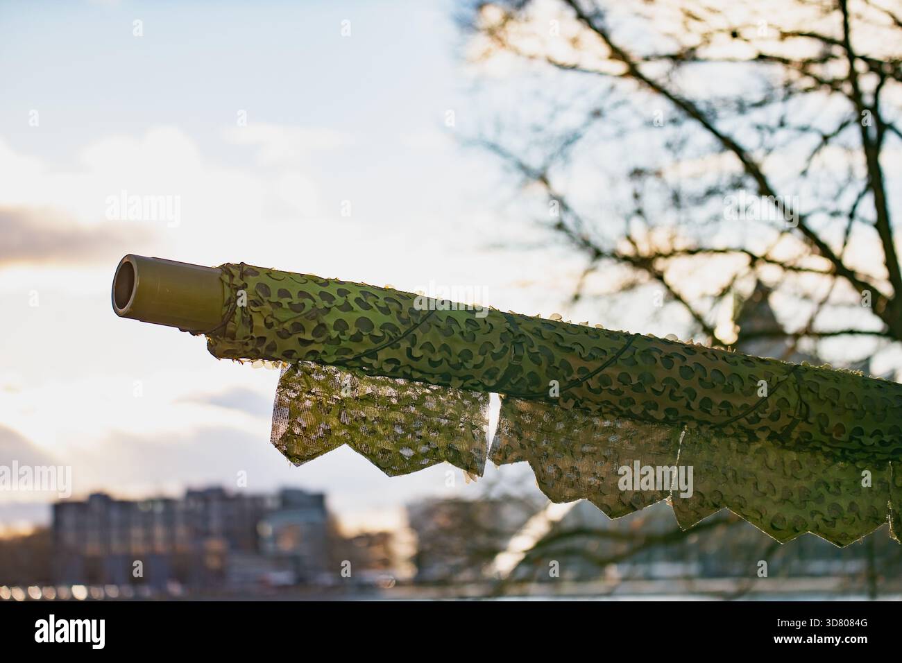 NATO battle tank gun shrouded in camouflage netting illustrating ...