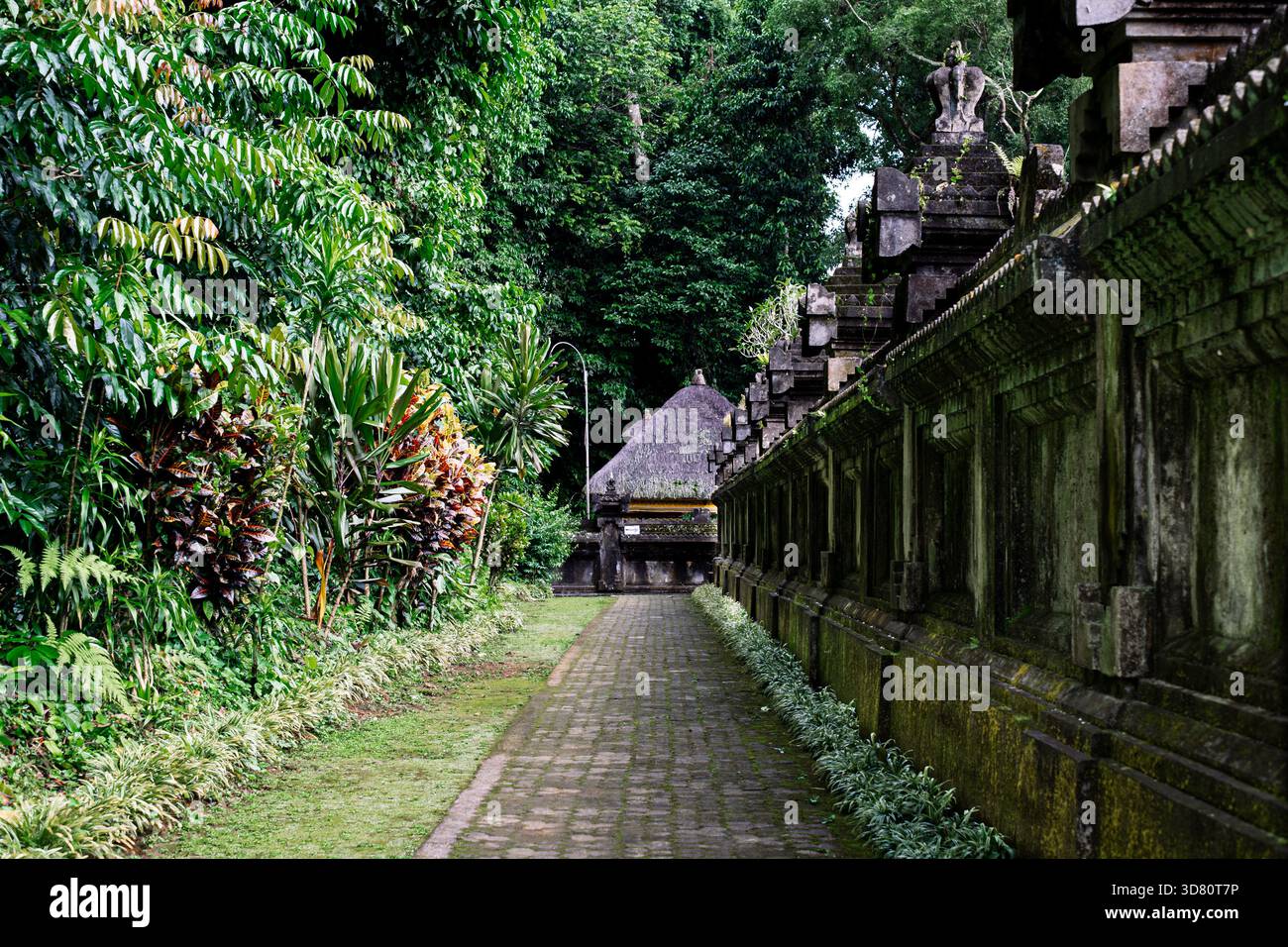 A paved stone pathway stretches between a moss-covered decorative stone ...