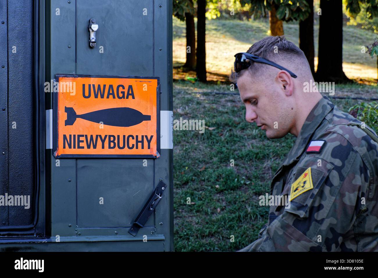 Polish soldier next to a warning sign for unexploded ordnance ...