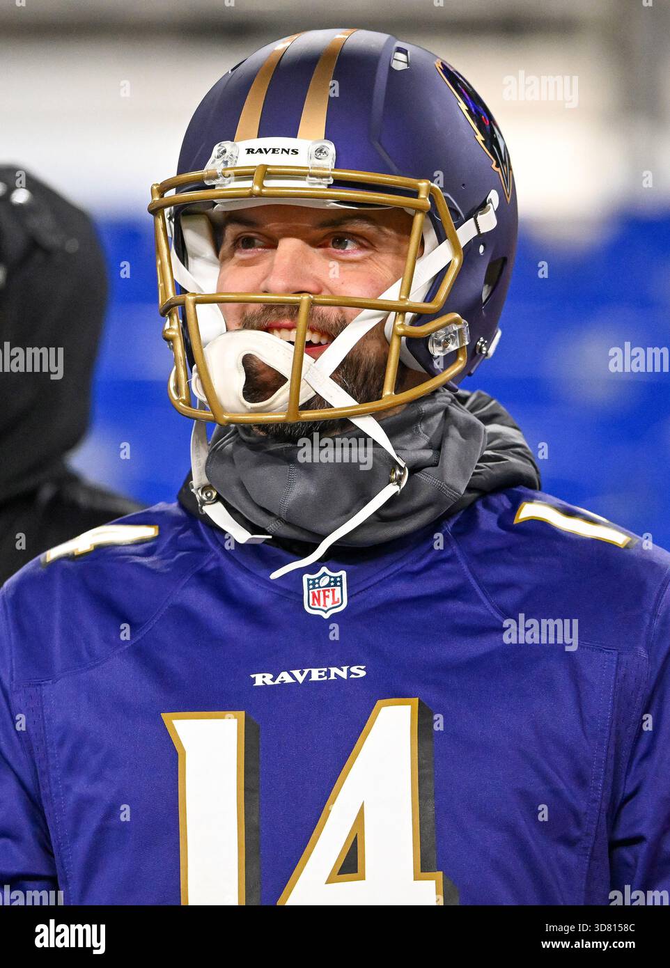 A Baltimore Ravens fan wears a helmet and jersey as he watches warmups ...