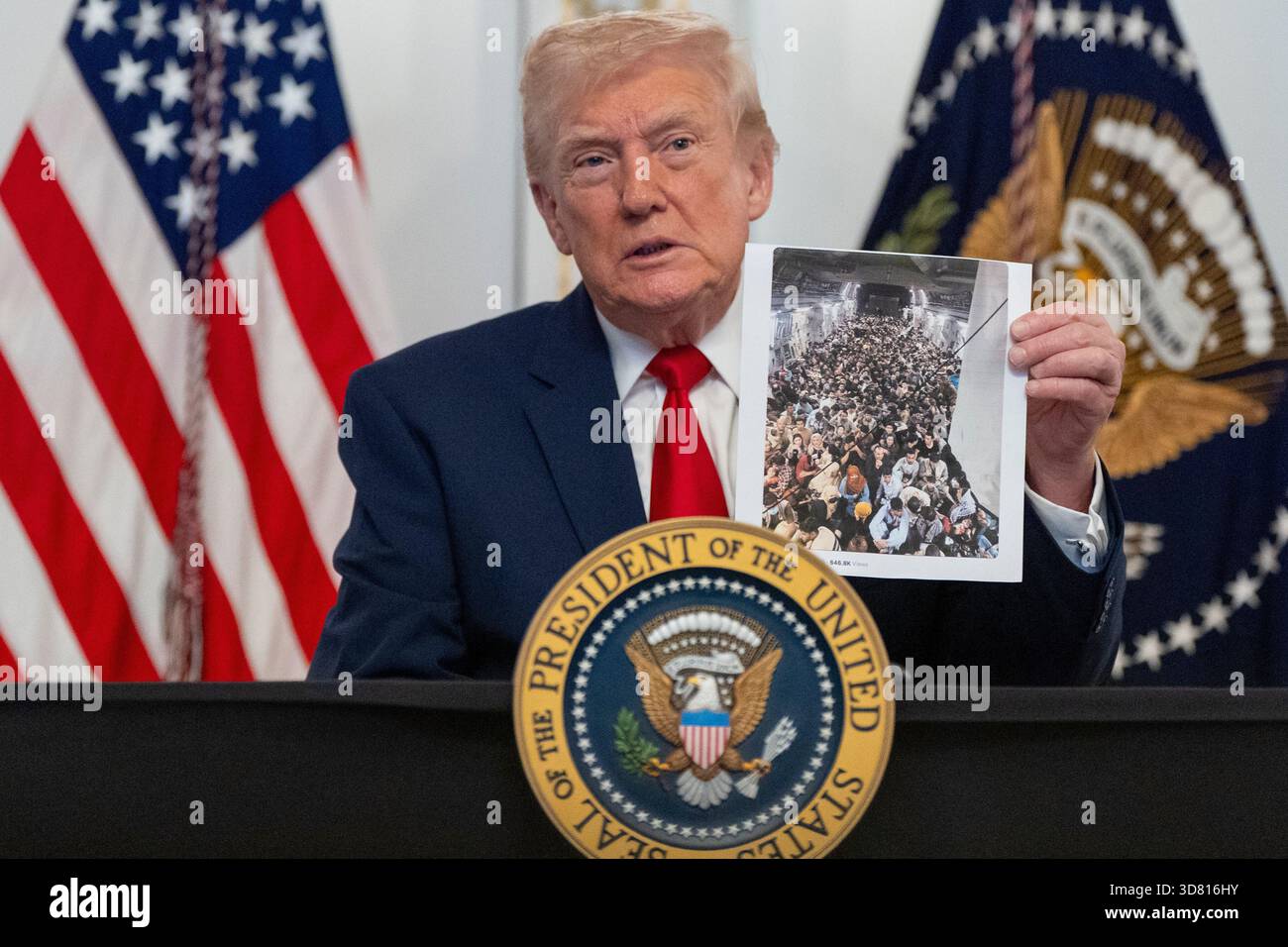 President Donald Trump holds up a photo as he speaks to troops via ...