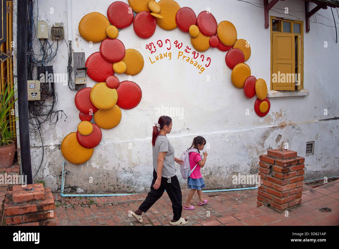 Locals walk past a decorated wall in the UNESCO World Heritage city of ...
