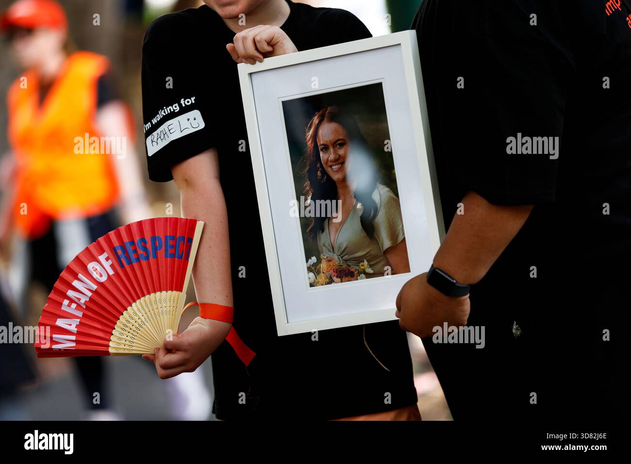 A participant is seen holding a photo of a victim during the Walk ...