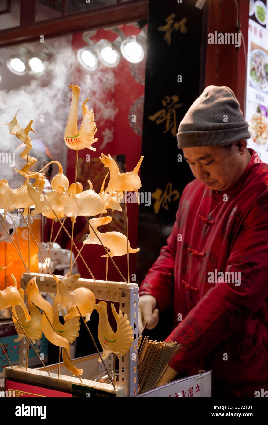 Artisan shaping delicate sugar animal figurines at a night street stall ...