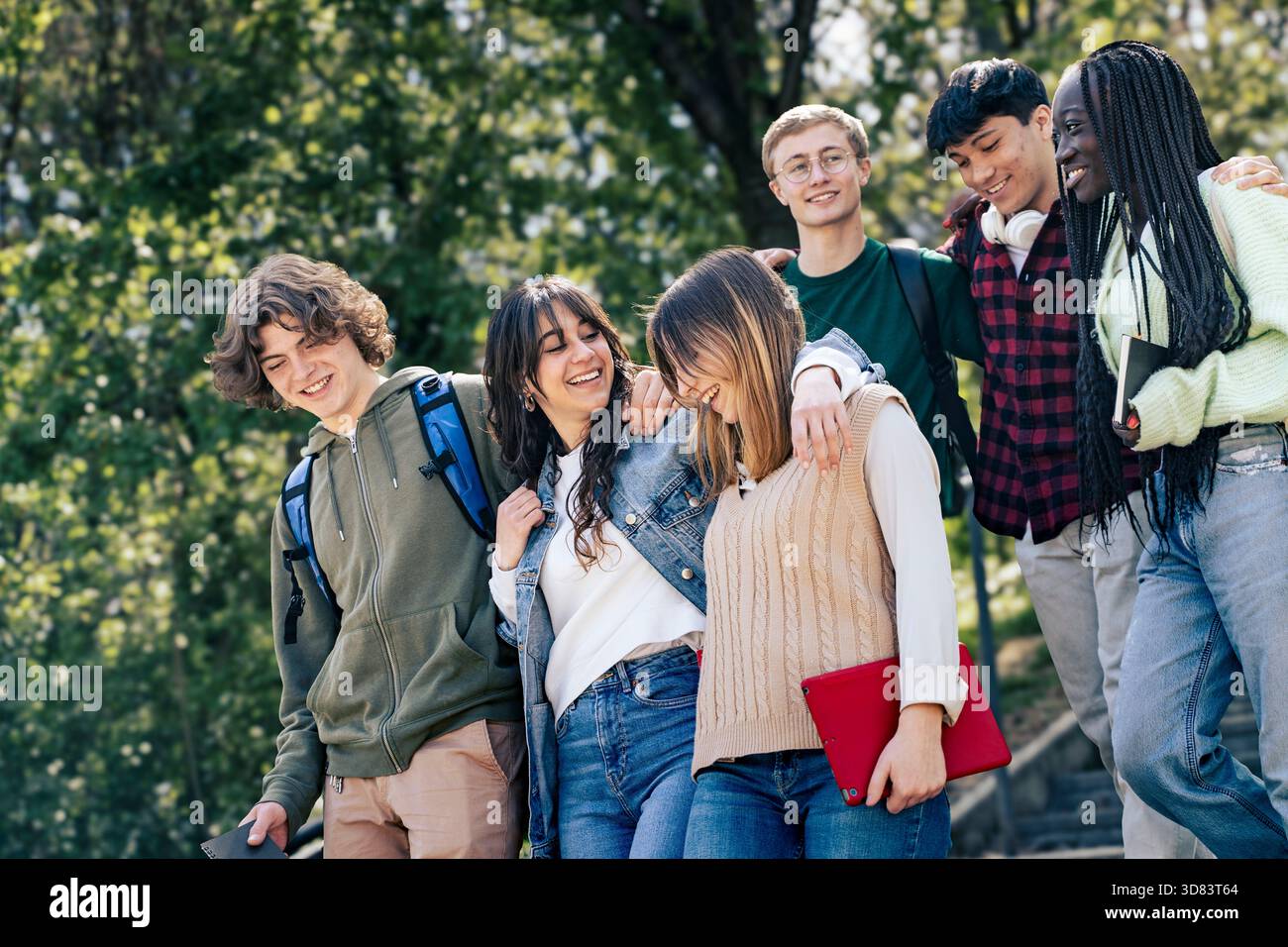 A group of diverse young students walking together outdoors on campus ...