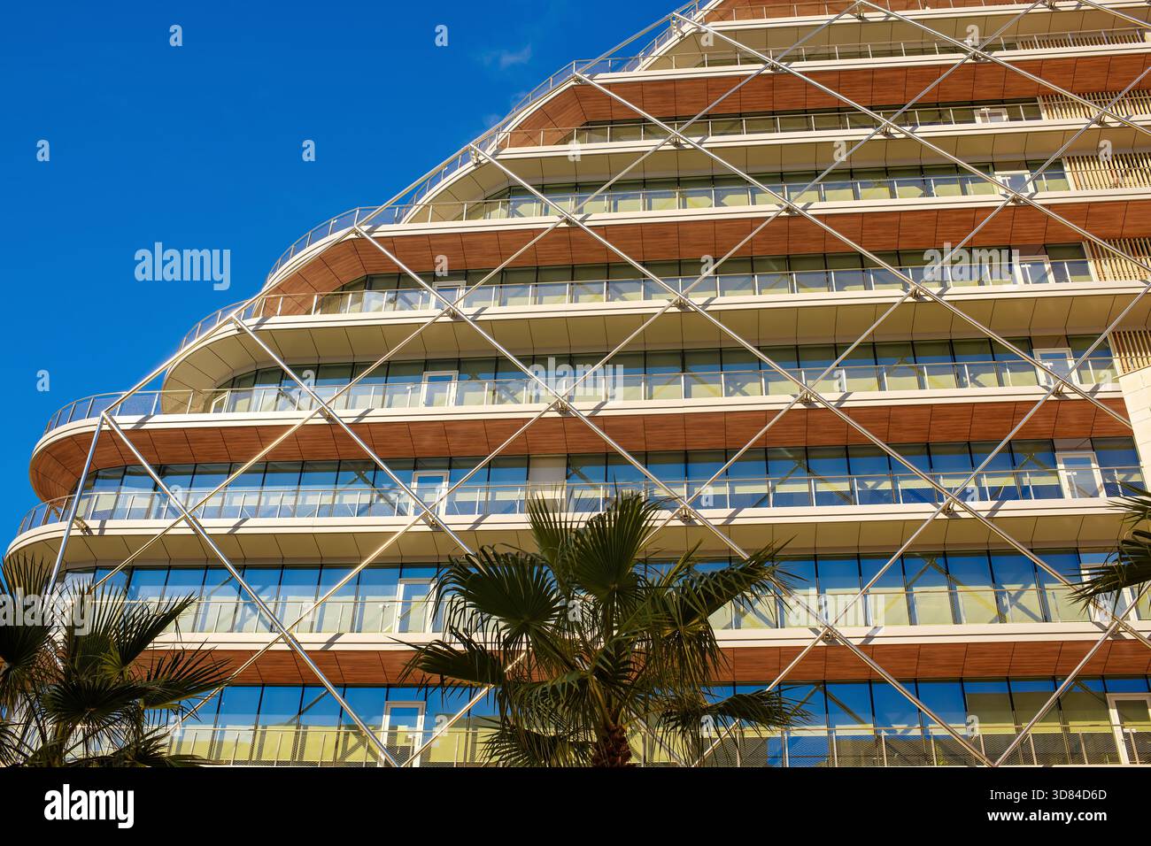 The building, with its glass facade reflecting the sky and angular ...