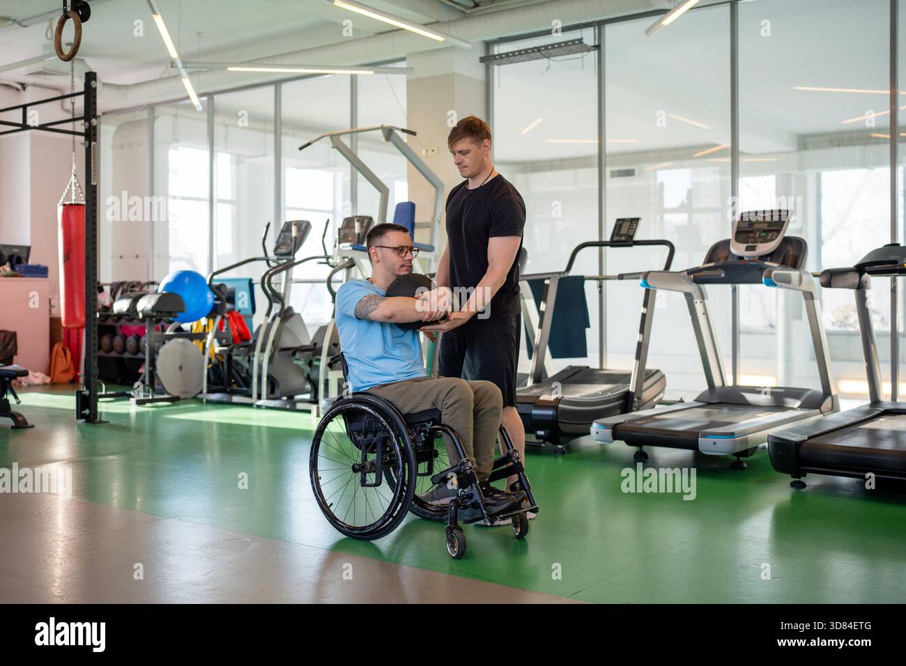 Personal sports trainer assists disabled sportsman in wheelchair with ...
