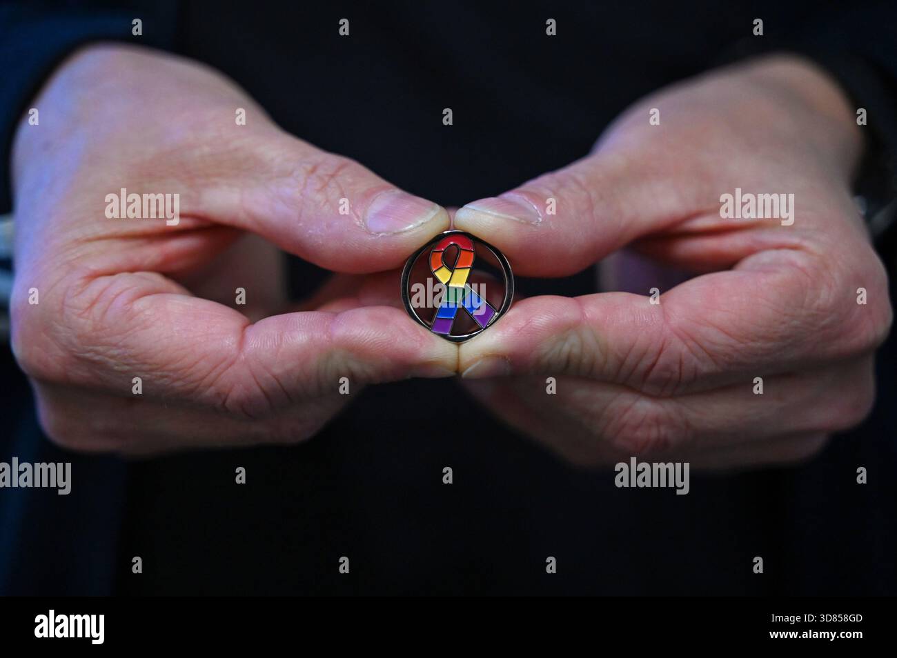 PRODUCTION - 27 November 2025, Berlin: A man at Berliner Aids-Hilfe e.V. holds a badge with a ...