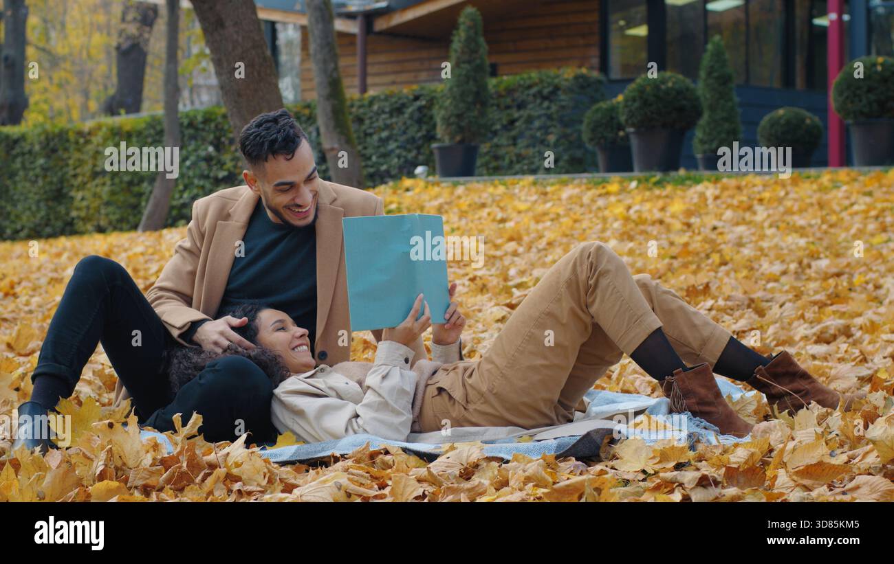Couple date outdoors in romantic autumn park with reading book Hispanic ...