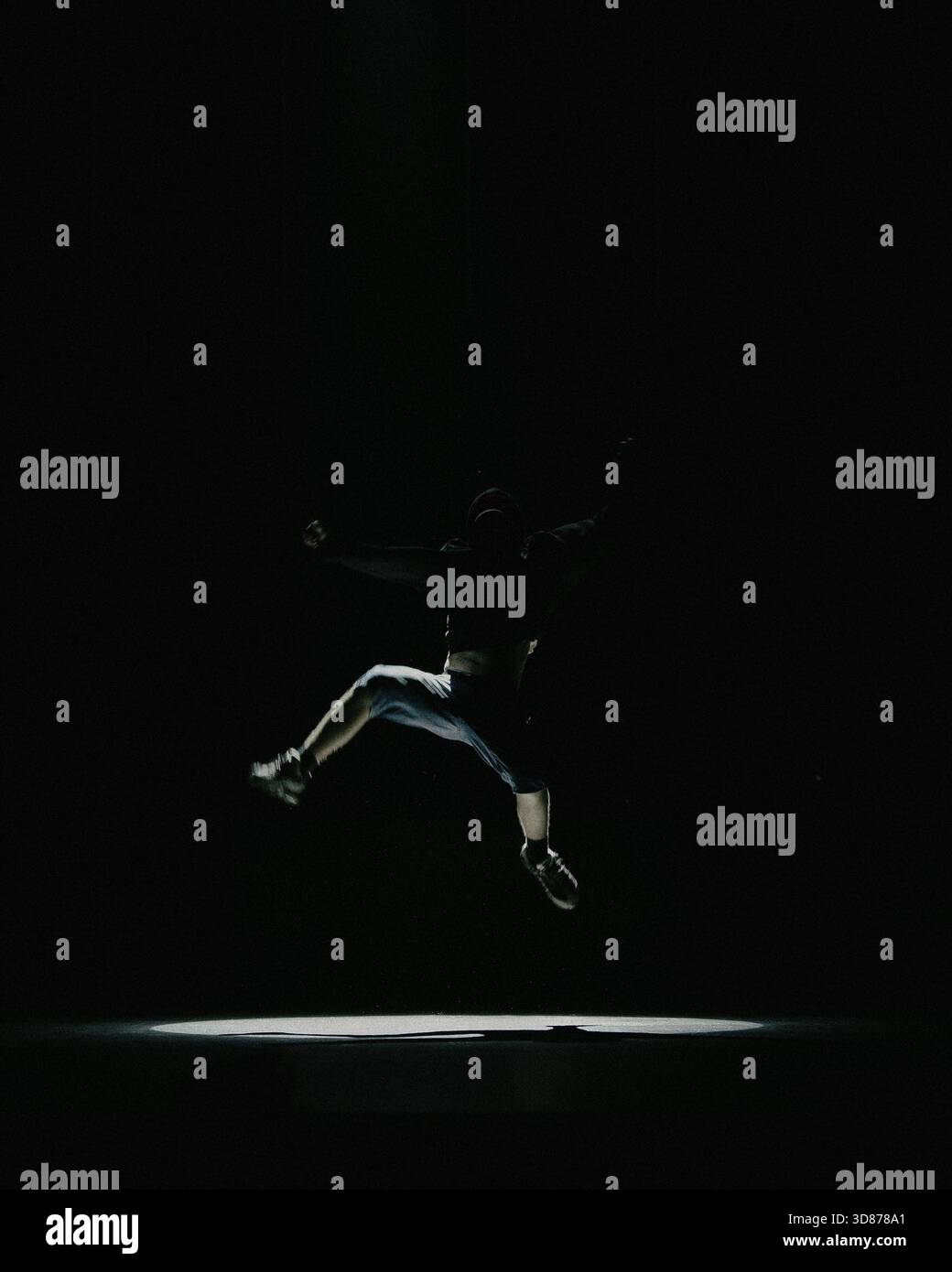Urban dancer mid-air kicks under spotlight with fierce emotional charge ...