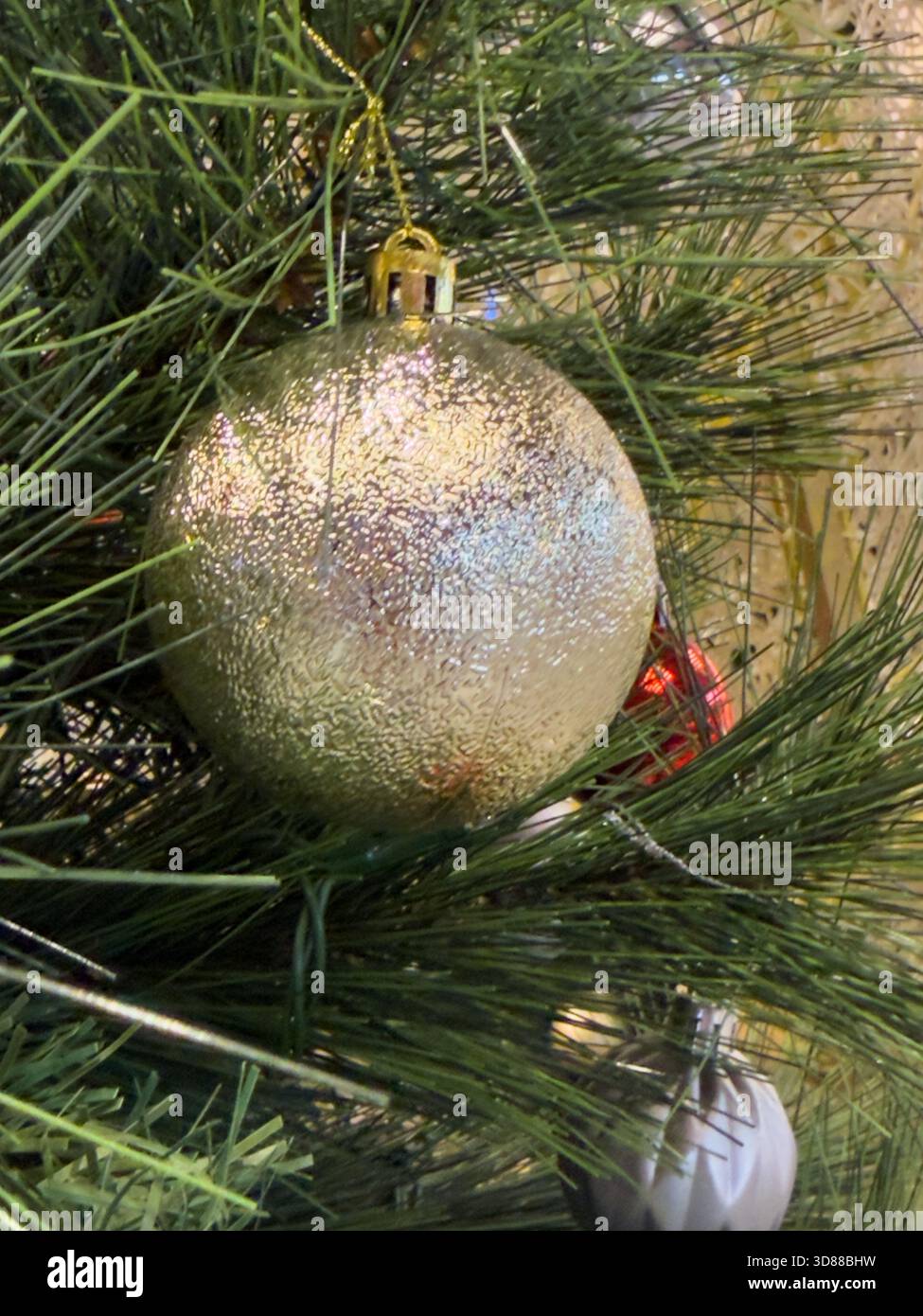 A shimmering gold, textured spherical ornament hangs prominently on an ...