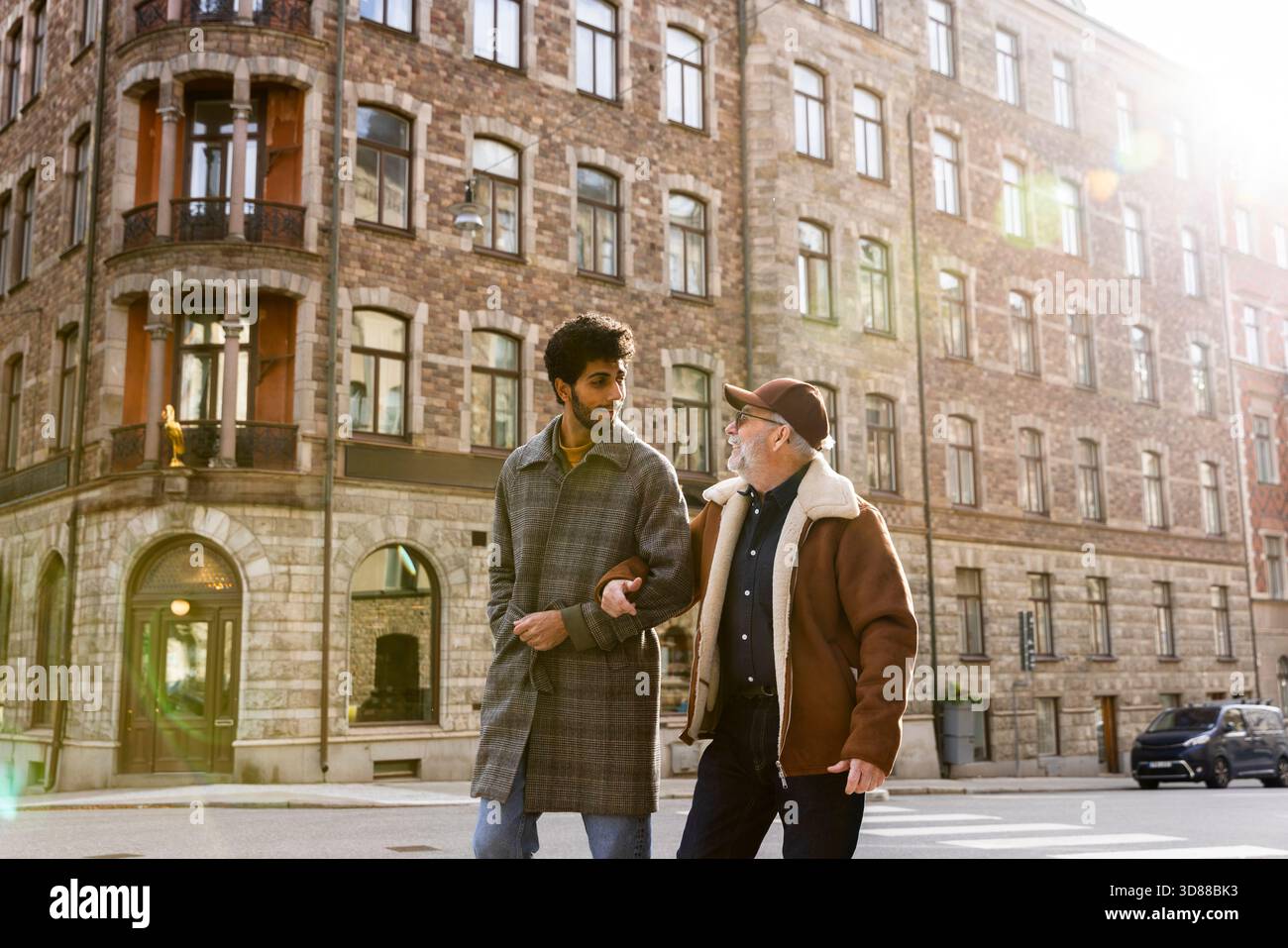 Senior man walking arm in arm with son at city street Stock Photo - Alamy