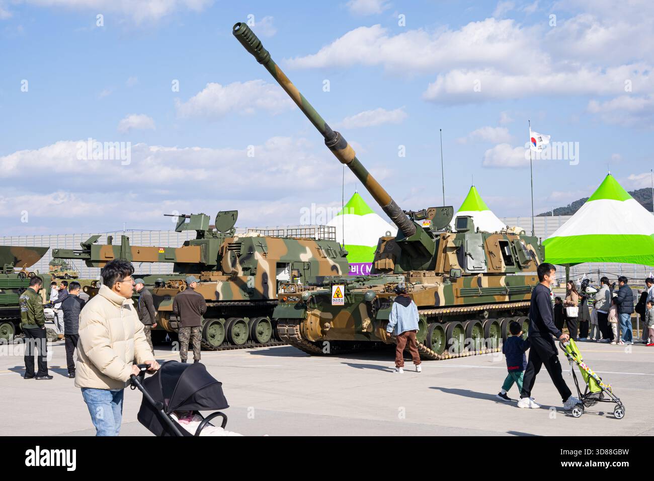 Visitors explore large military artillery vehicles at an outdoor ...