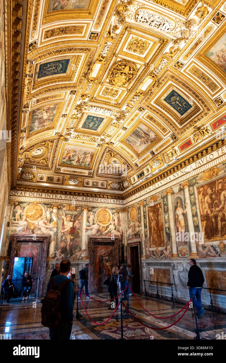 Visitors admire the ornate ceiling and walls of a room in the Vatican ...
