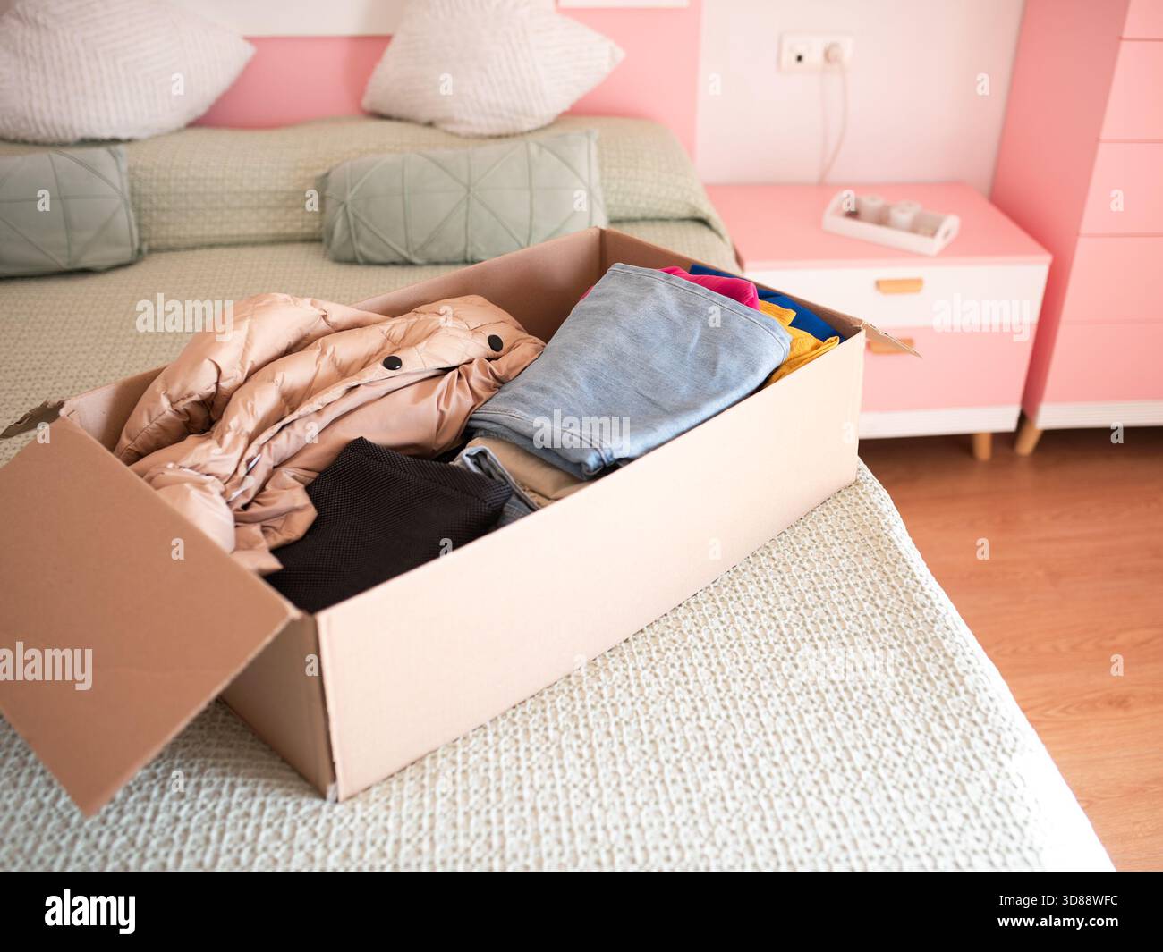 Cardboard box contains various clothing items, including jackets and ...
