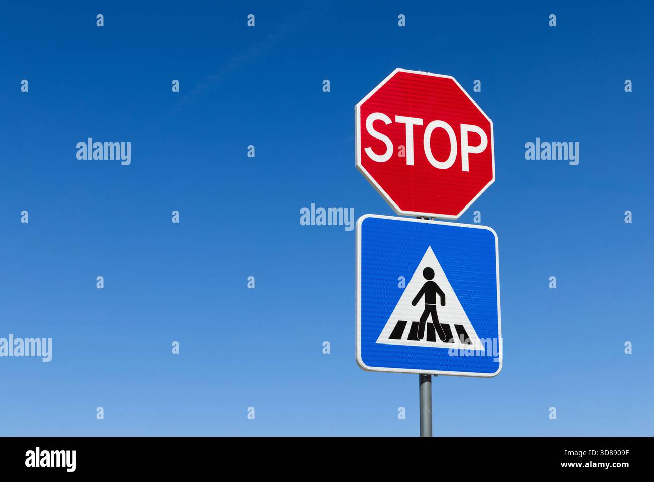 A red octagonal STOP sign positioned above a blue triangular pedestrian ...
