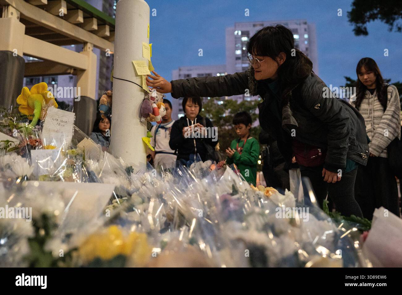 A woman sticking a note onto a lamppost near the scene of where a major ...
