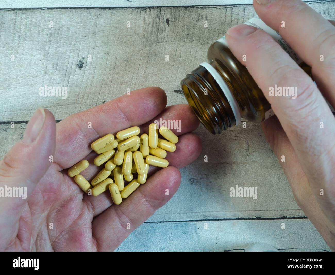 Hand pouring yellow capsules from hi-res stock photography and images ...