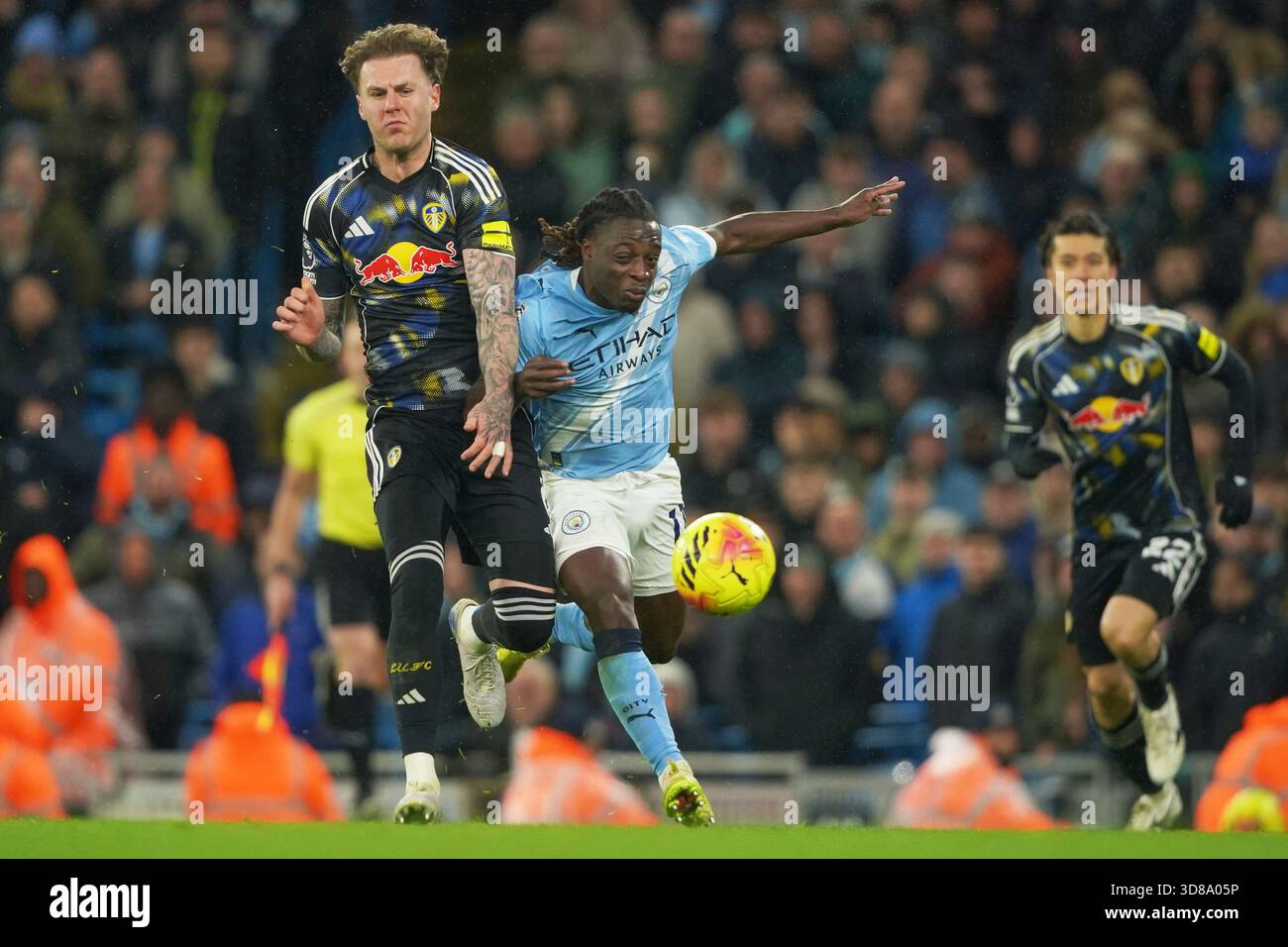 Manchester City's Jeremy Doku, centre, challenges for the ball with ...