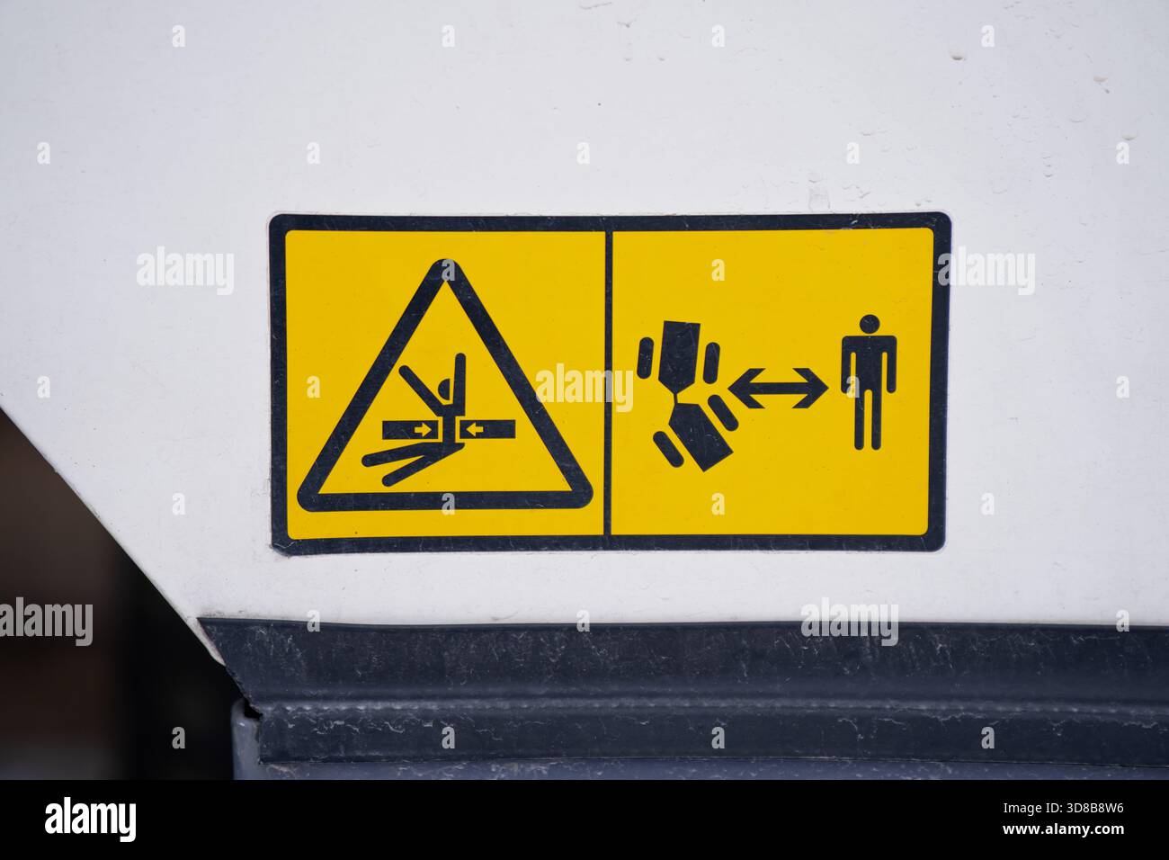 Yellow warning sign on machinery showing danger of crushing and ...