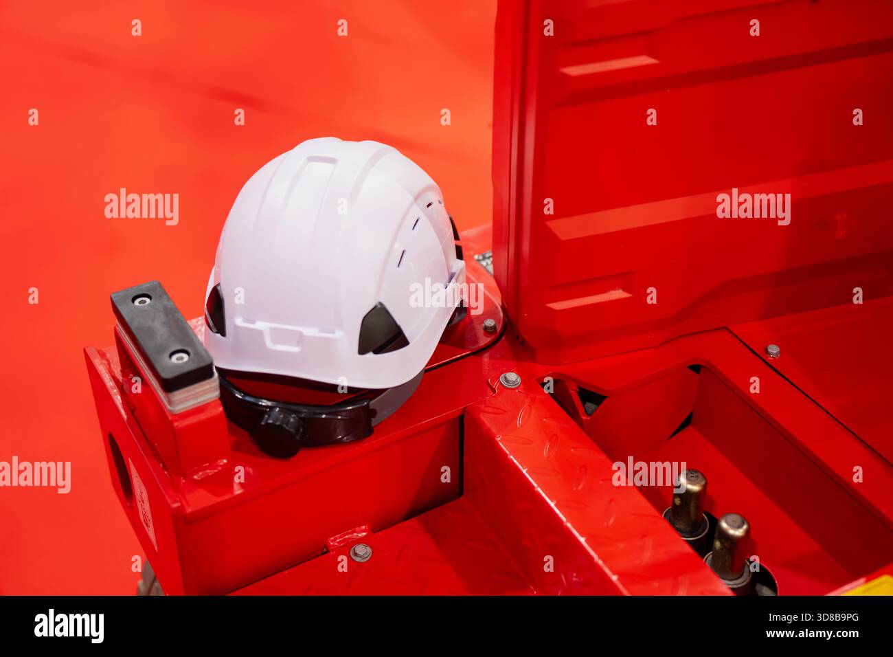 Protective white hard hat resting on red metal equipment platform as ...