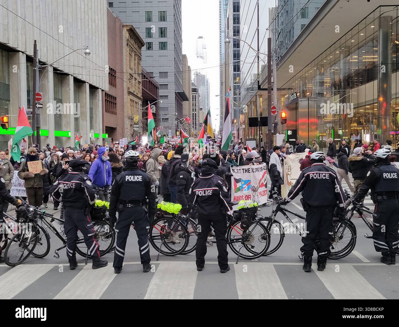 Toronto police officers watch people marching in an International Day ...