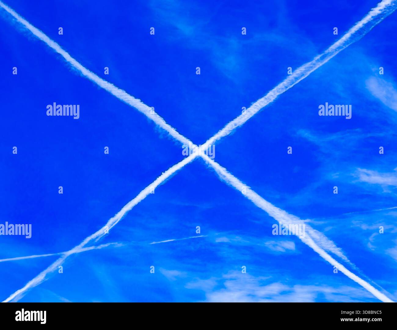 Dramatic crossed airplane contrails creating an “X” shape against a ...