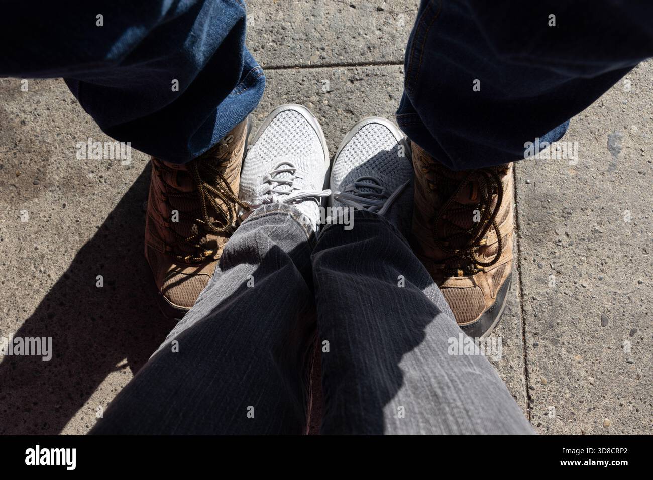 Two pairs of feet touch toe-to-toe in bright sunlight, creating a ...