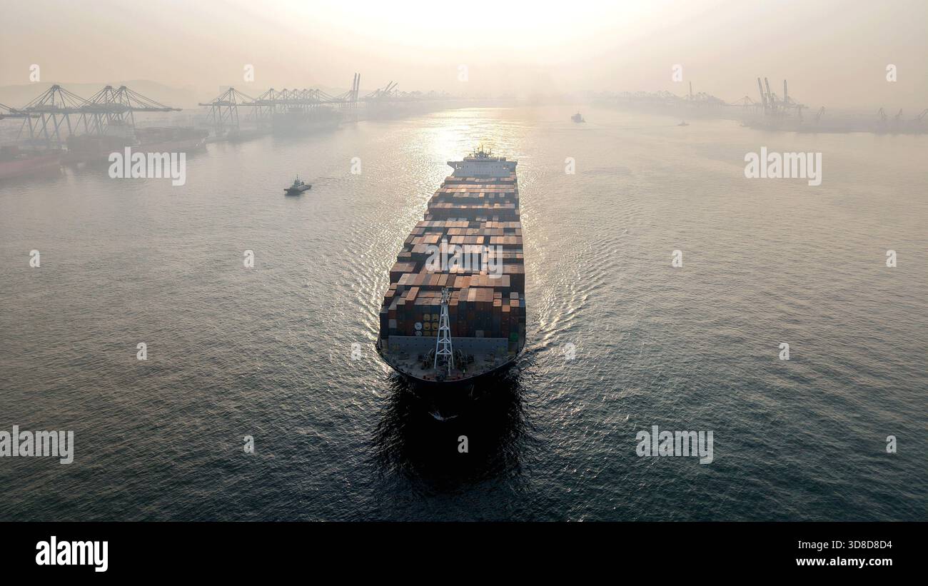 A container ship sails through the harbor in Qingdao in eastern China's ...