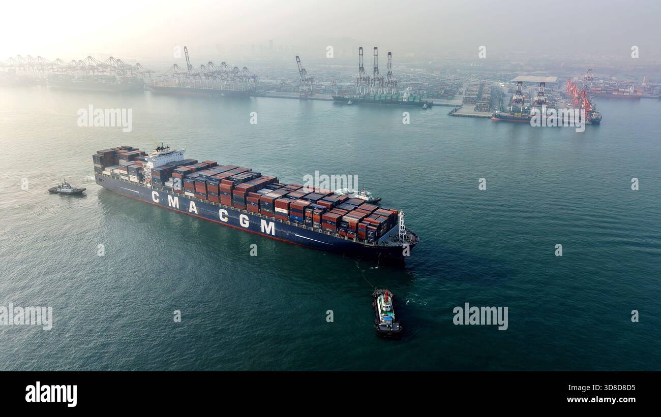 Tugboats move a CMA CGM container ship in a harbor in Qingdao in ...