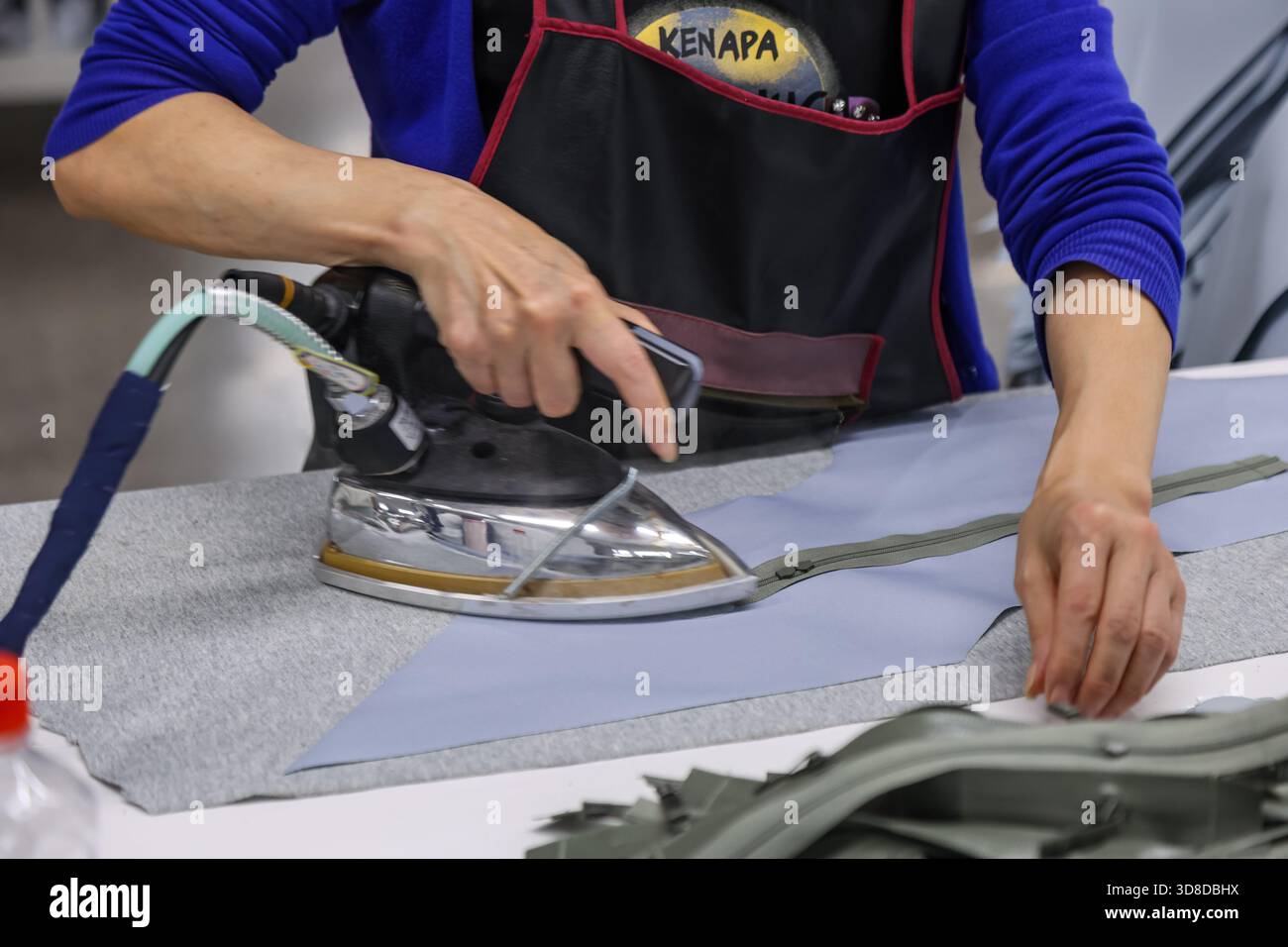 A man irons a part at an apparel factory making waterproof jackets in ...