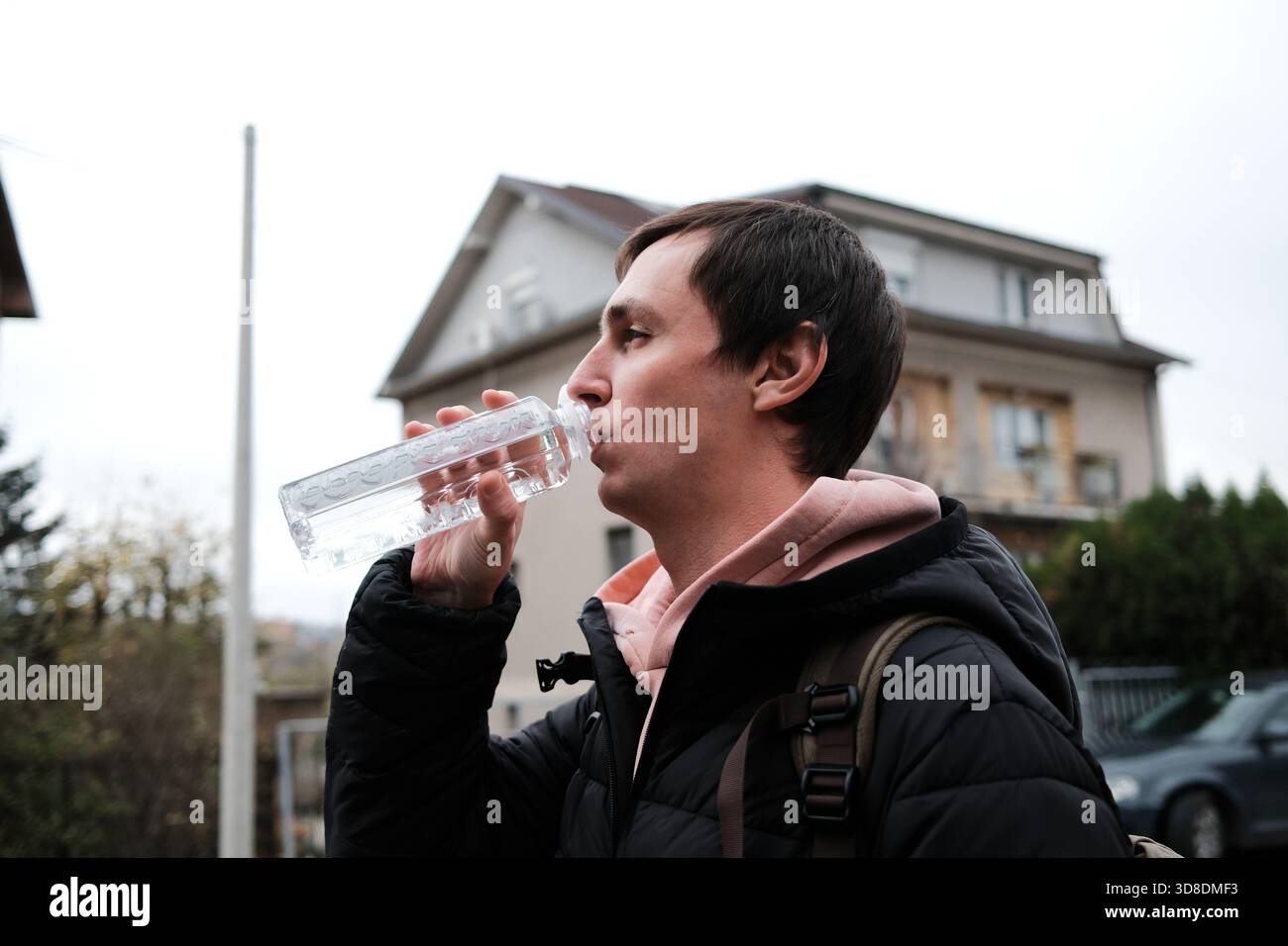 A man drinks water from a bottle during a walk. The moment shows daily ...