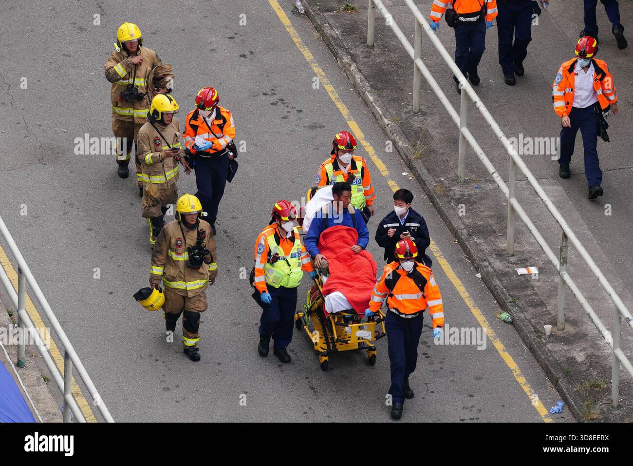 Paramedics pulling a firefighter on a stretcher as a major fire engulfs ...