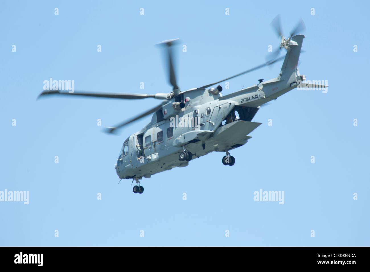 Military helicopter in flight with landing gear deployed against a ...